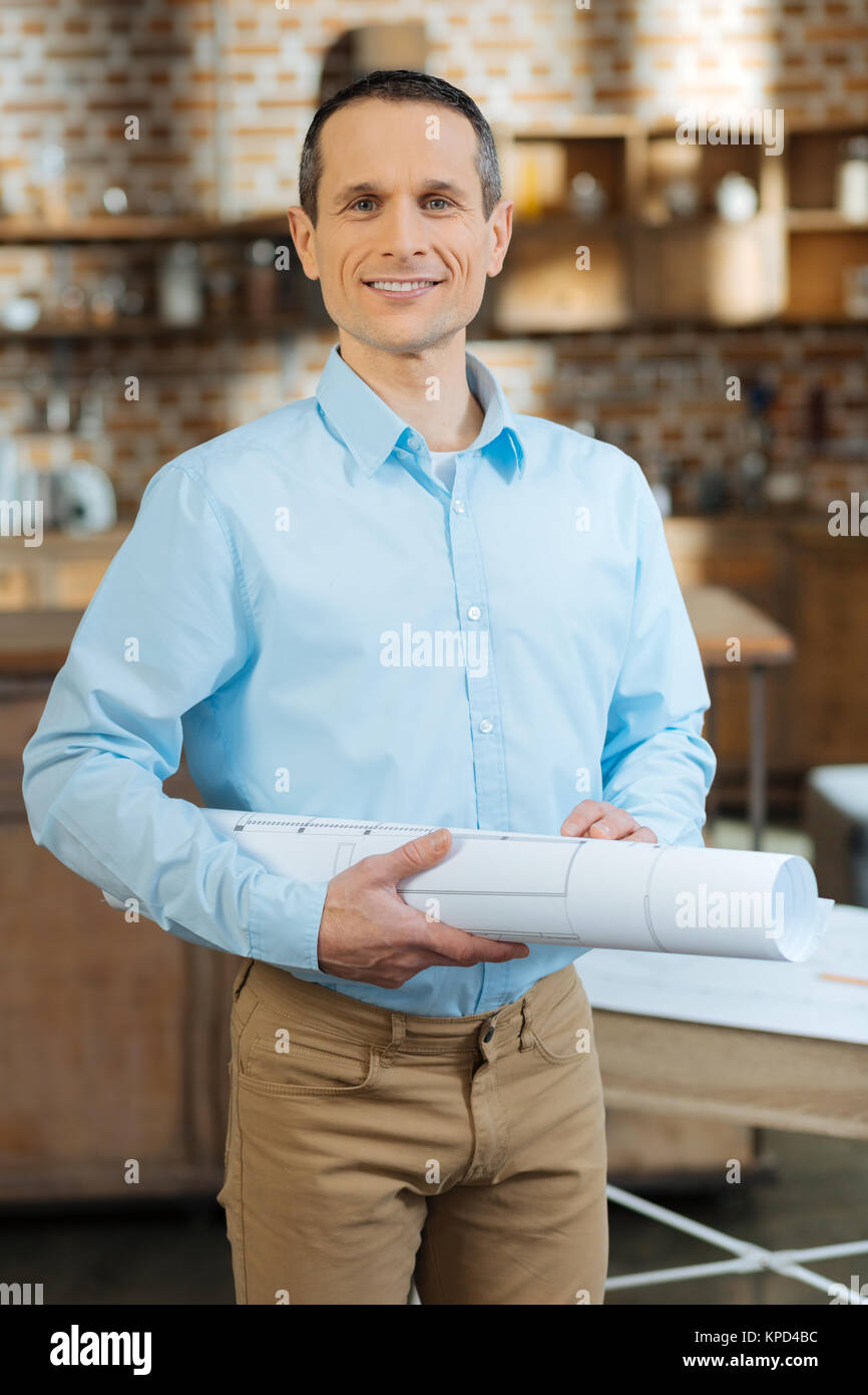 Competent worker holding rolled sketch Stock Photo - Alamy