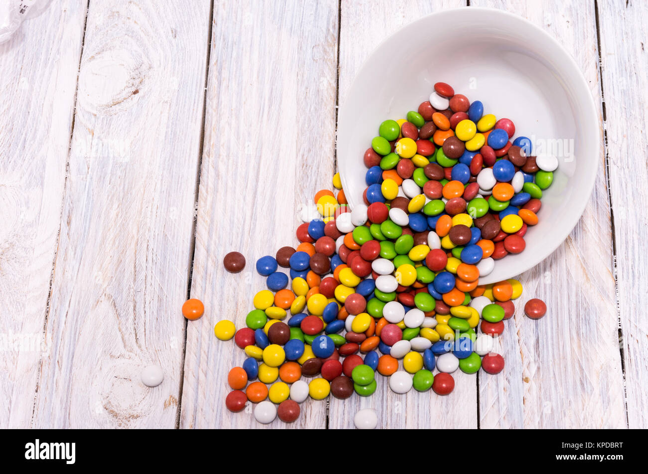 Inverted plate. Spilled candy on the table. White wooden table Stock ...