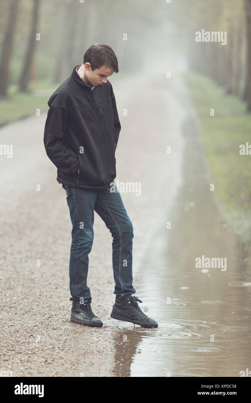 Sad teenager putting foot in puddle Stock Photo - Alamy