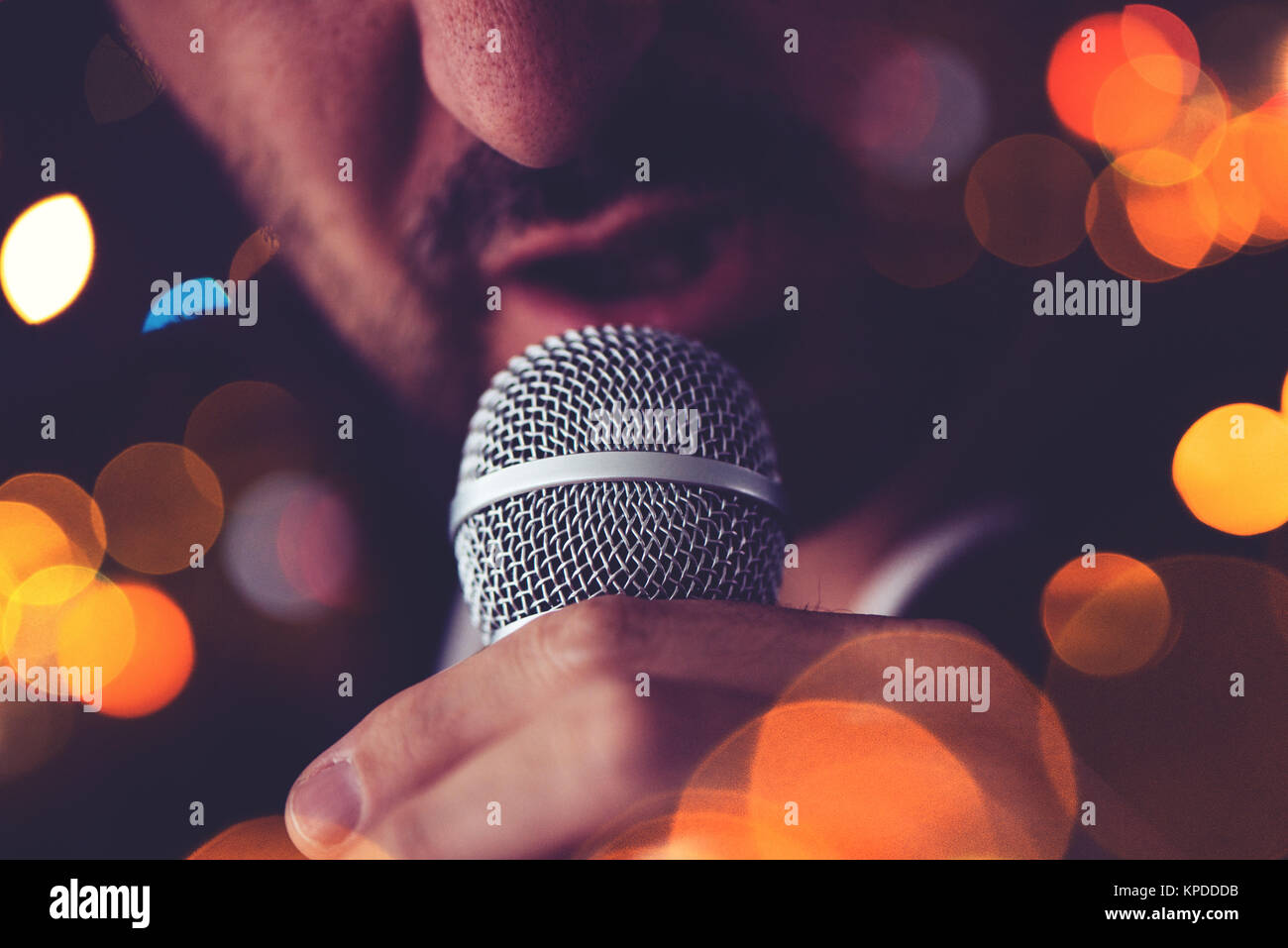 Man sings karaoke in a bar at night with festive bokeh light effect ...