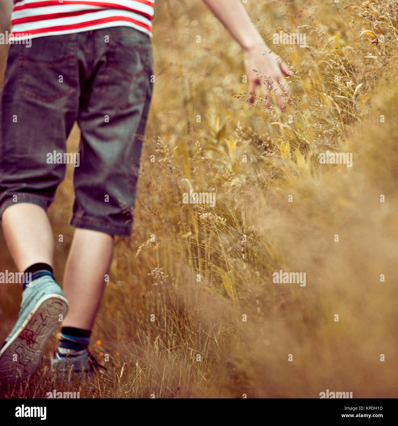 Young man walking through a grassy field Stock Photo - Alamy