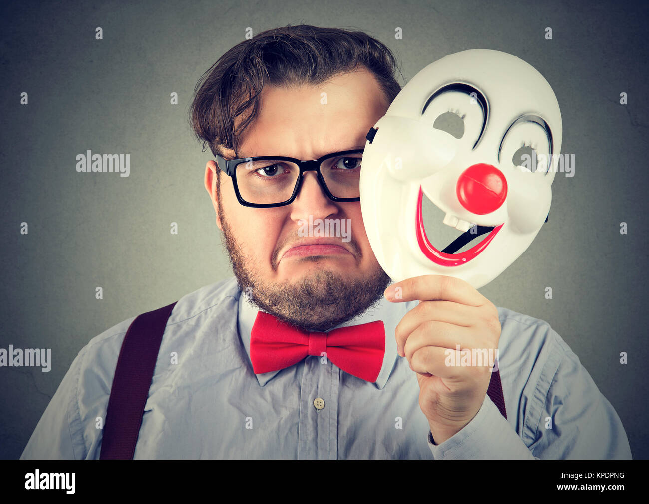 Young upset man frowning while looking at camera and holding happy ...