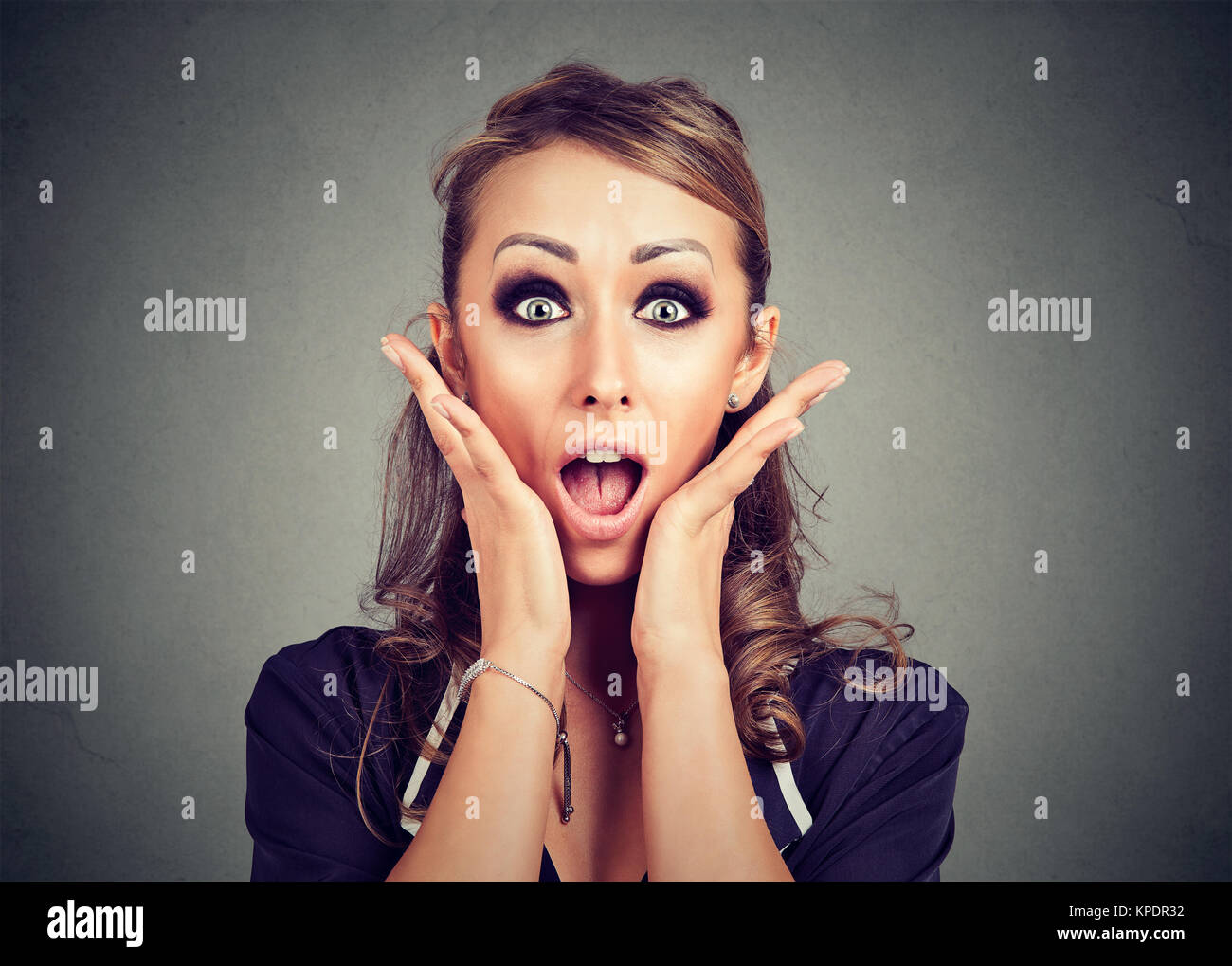 Headshot of young model with makeup touching cheeks in expression of ...