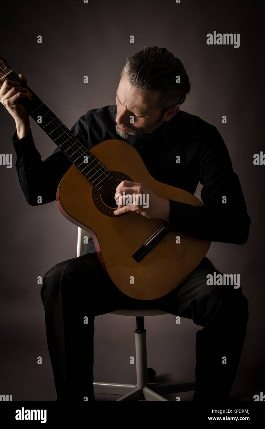 Portrait of a guitarist playing in a studio Stock Photo - Alamy