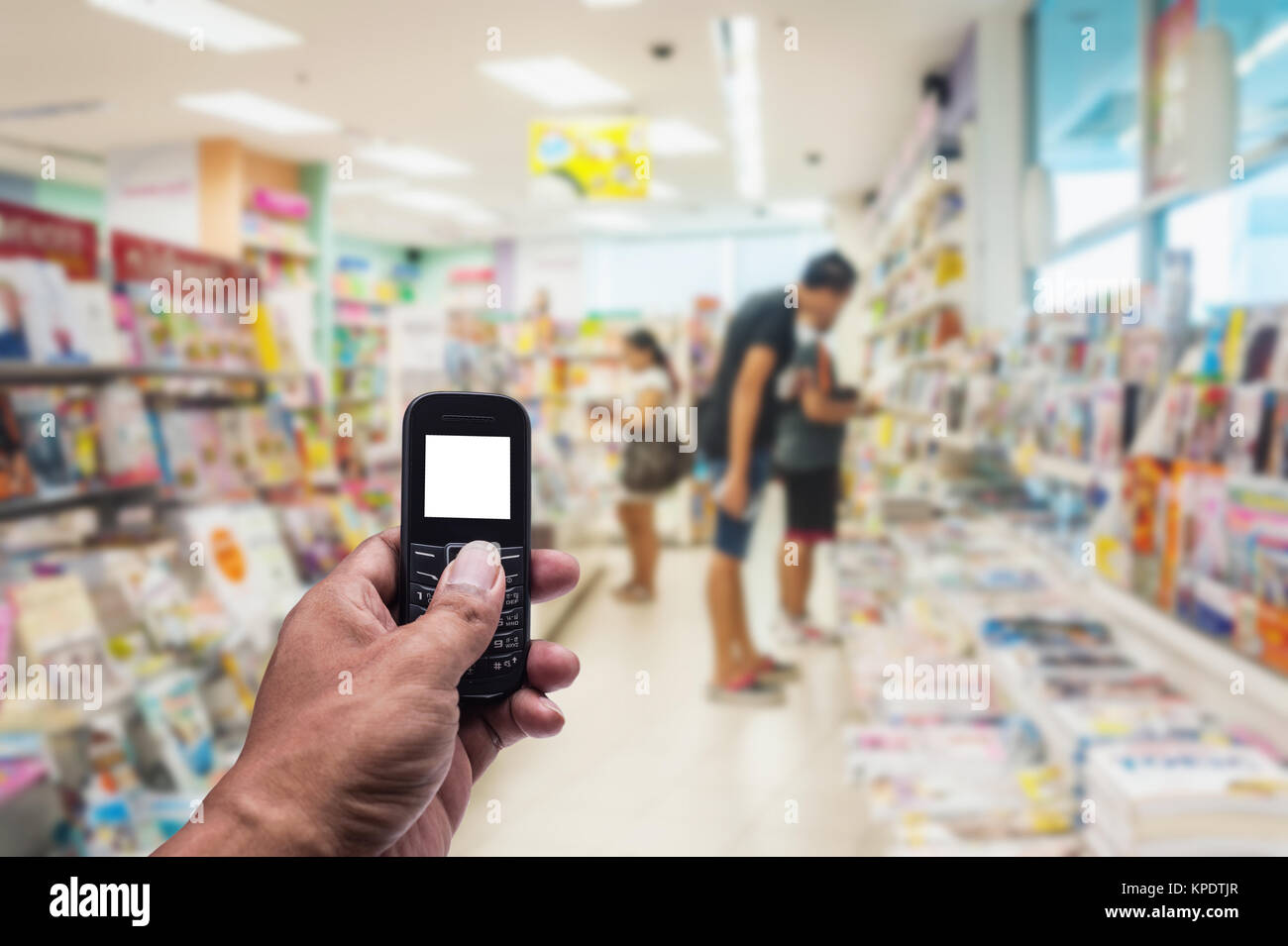 Phone white screen in hand on blurred book store Stock Photo - Alamy
