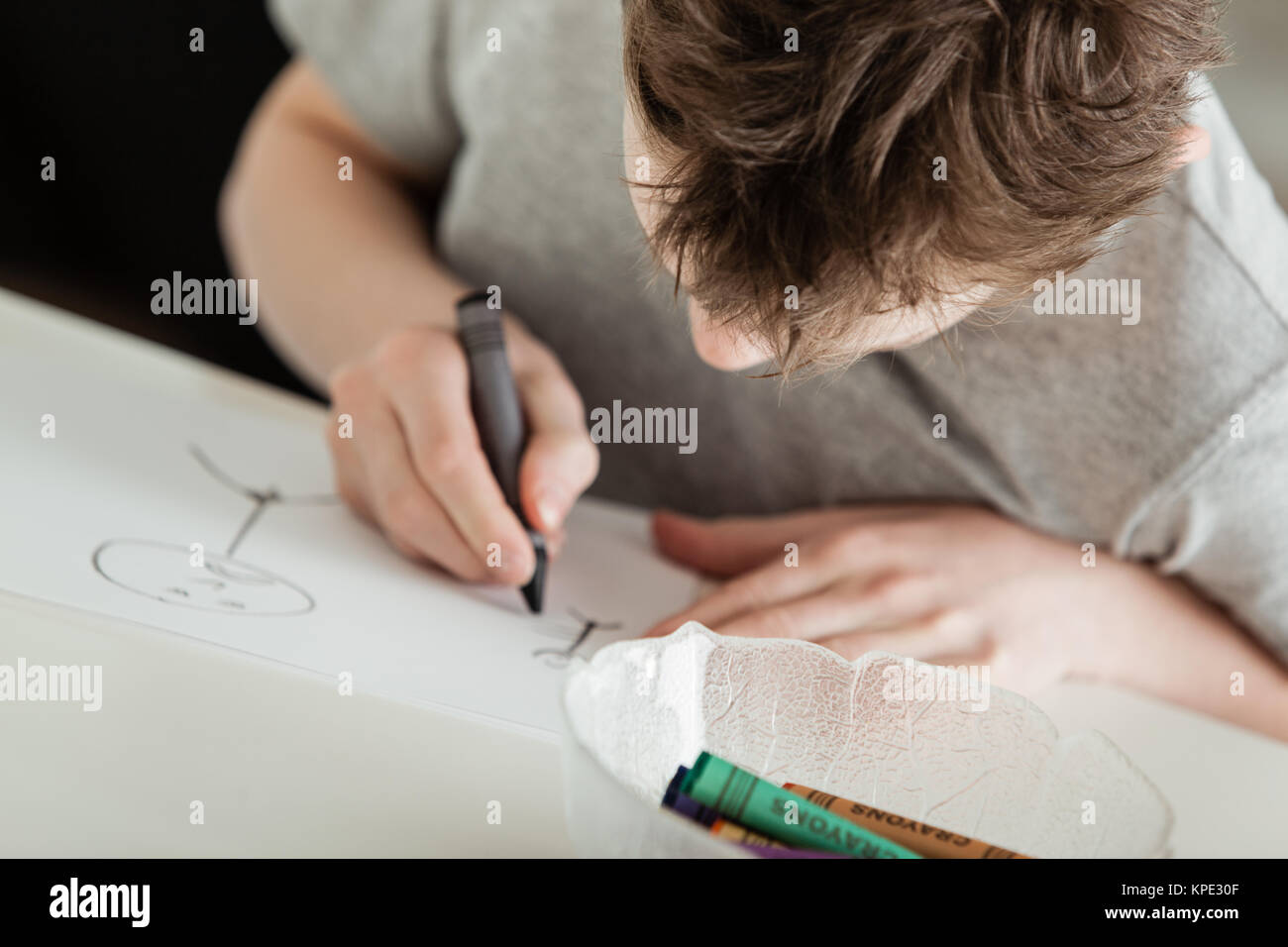 Young Boy Making Artwork Using Crayons at Table Stock Photo - Alamy