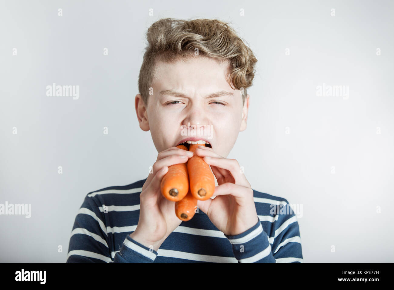 Boy Eating Three Large Carrots Stock Photo - Alamy