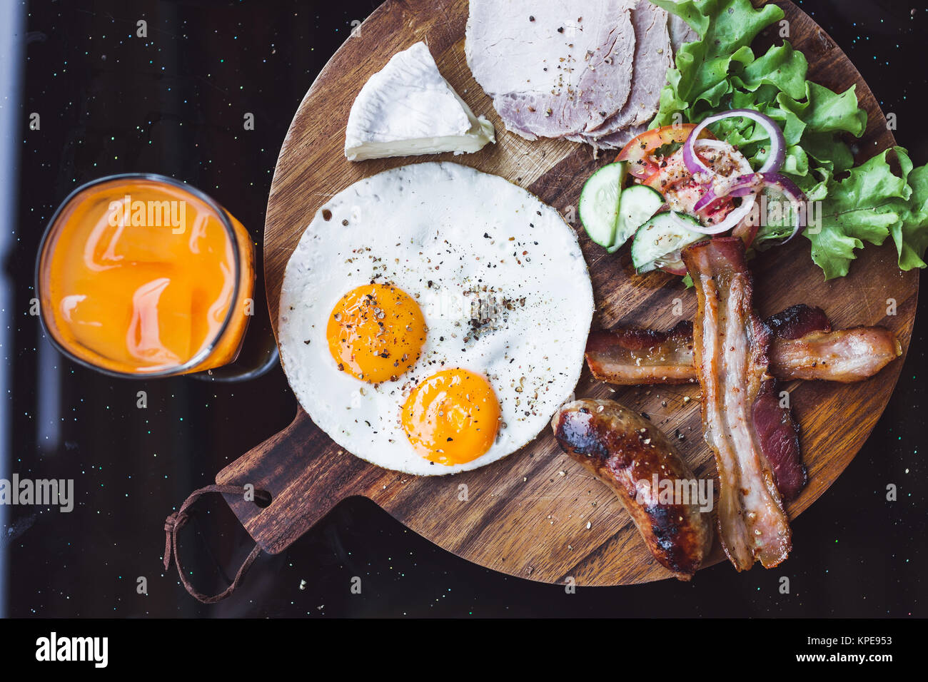 Breakfast with fried eggs, bacon and cheese camembert on wooden board ...