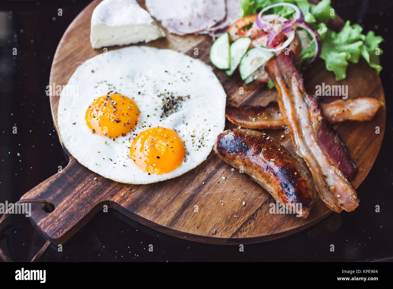 Breakfast with fried eggs, bacon and cheese camembert on wooden board ...