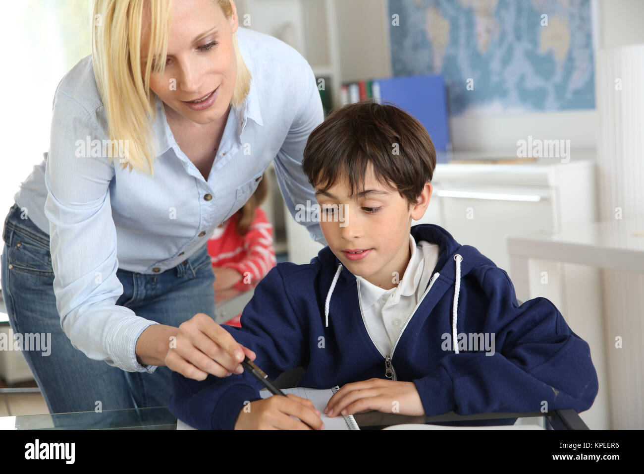 Teacher helping young boy with lesson Stock Photo - Alamy