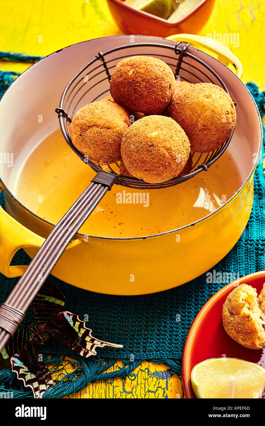 Brazilian national dish of bolhinos in frying basket over pot of oil on ...