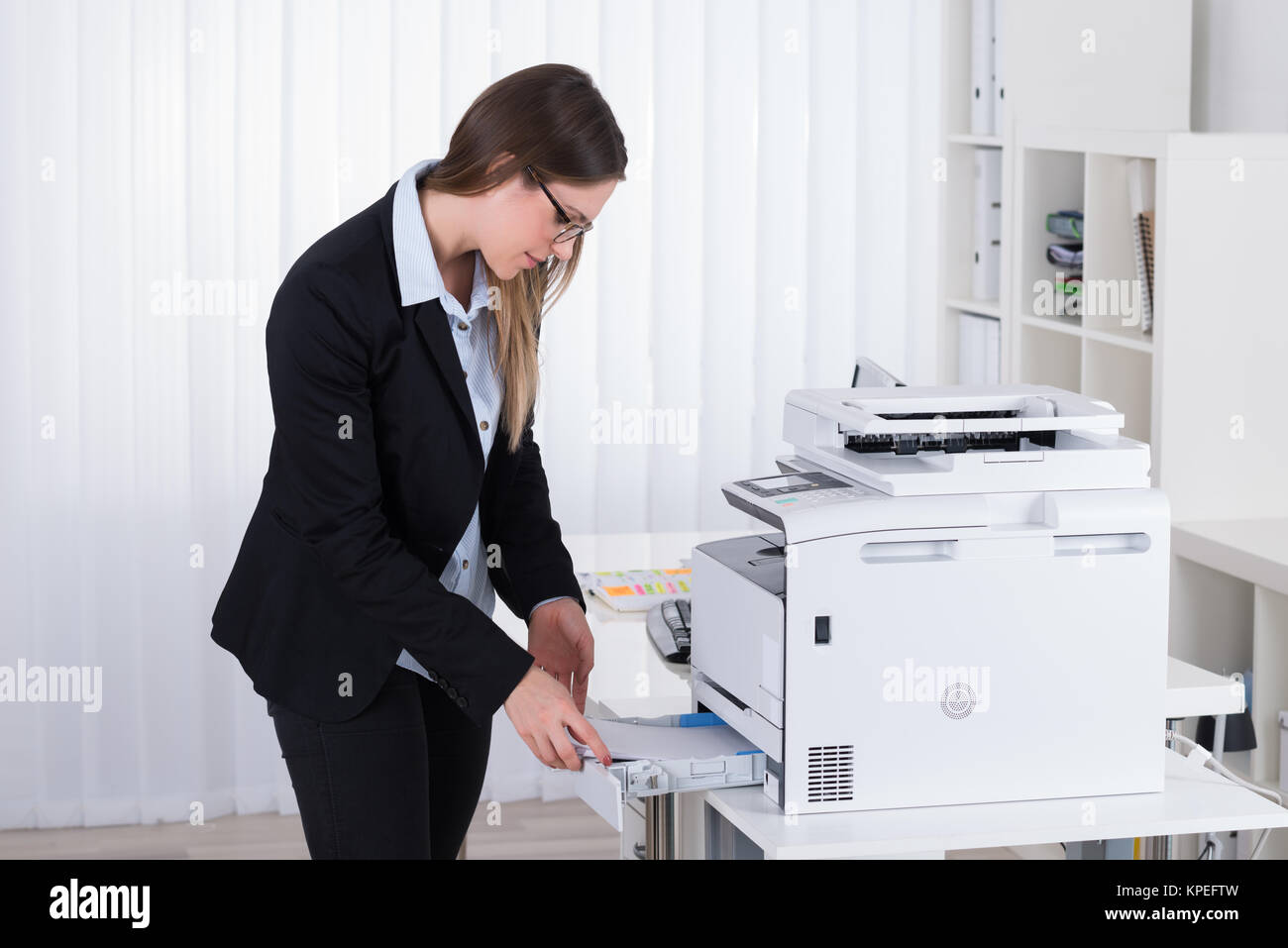 Businesswoman Putting Papers In Copy Machine Stock Photo - Alamy