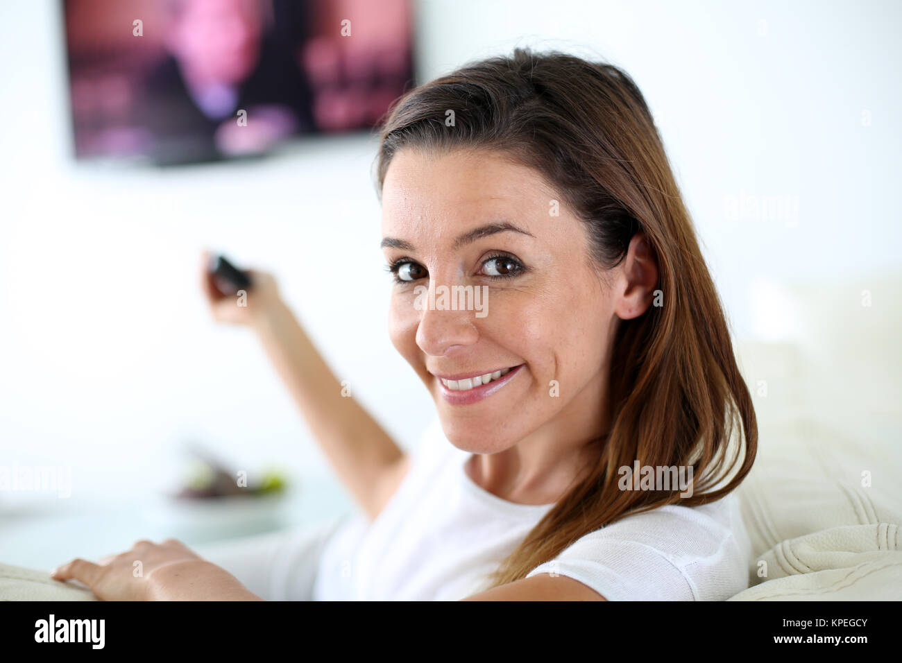 Portrait of young woman watching tv Stock Photo - Alamy