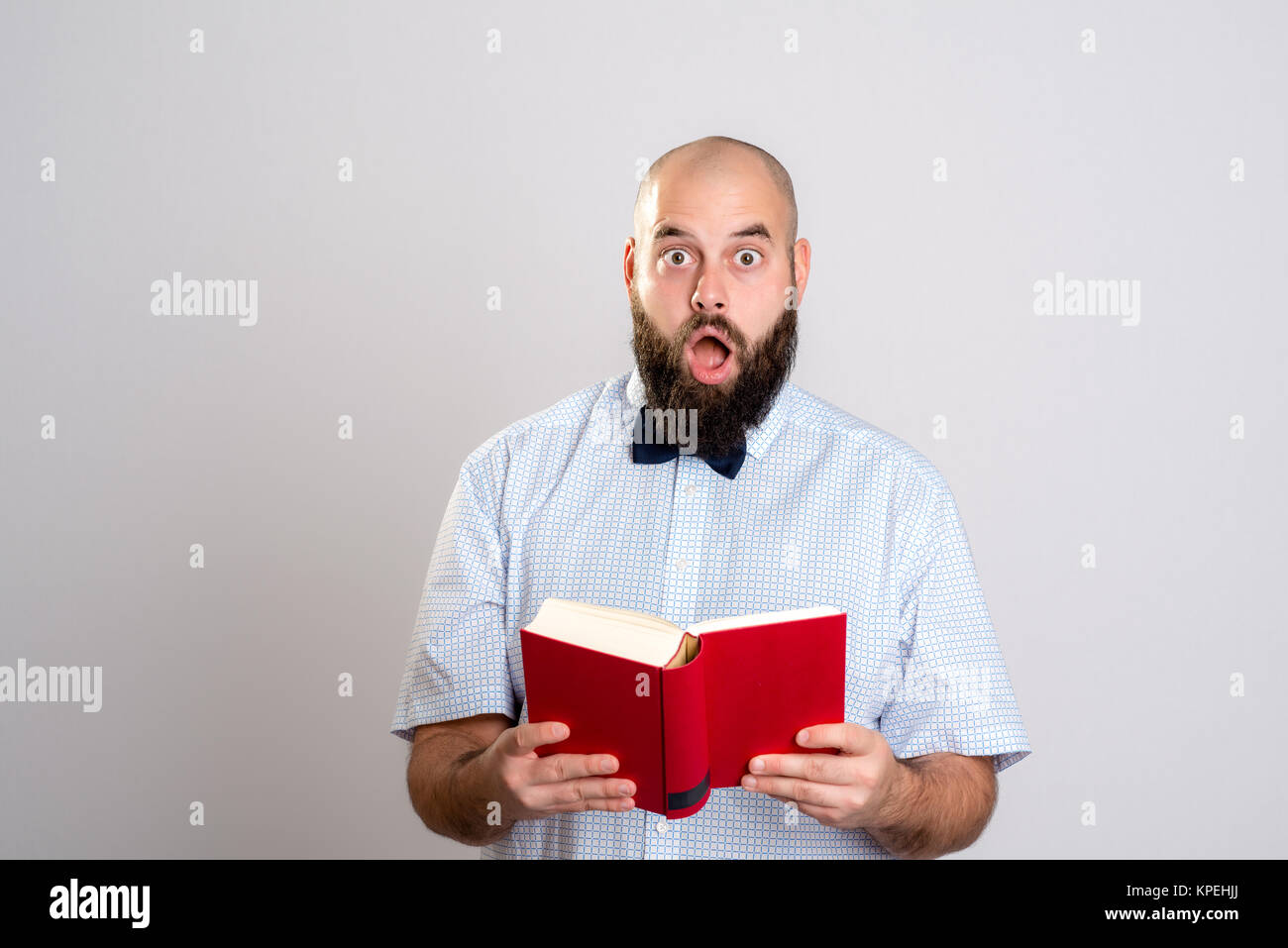 young bearded man reading a book in front of gray background Stock ...