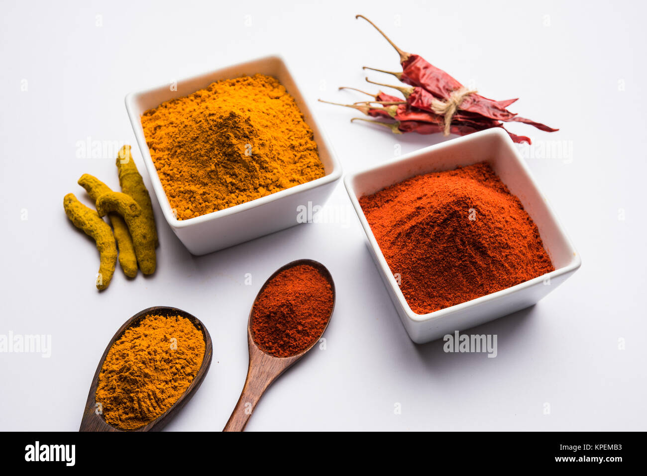 heap of turmeric and red chilli powder in a ceramic bowl on a white or ...