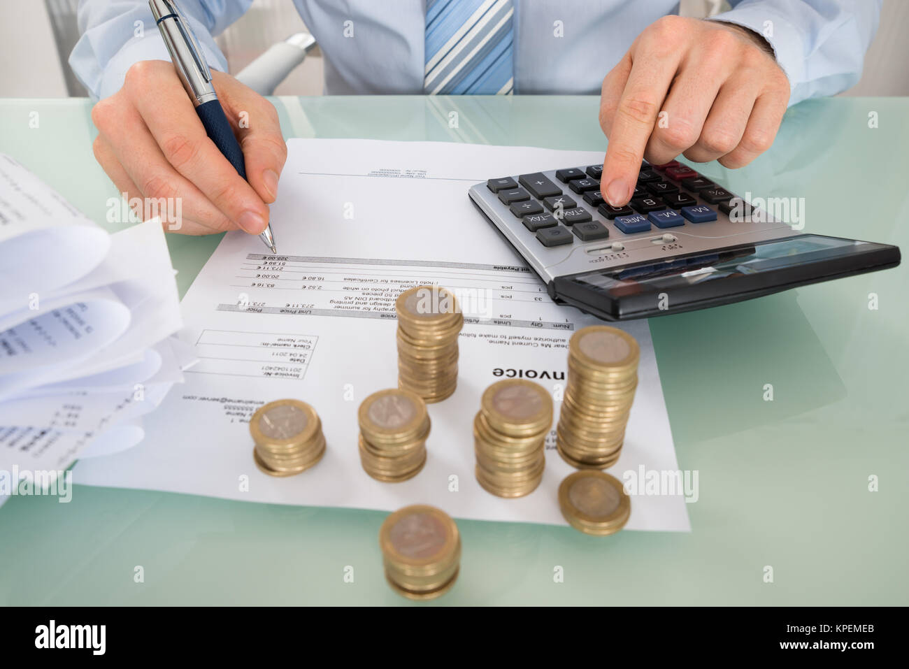 Businessman Calculating Invoice With Coins At Desk Stock Photo - Alamy