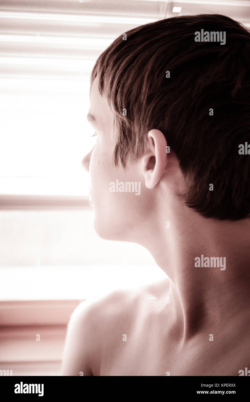 Thoughtful young boy staring out of a window Stock Photo - Alamy