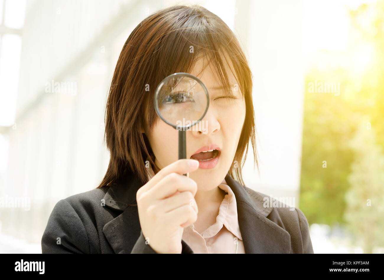Asian female looking through magnifier glass Stock Photo - Alamy