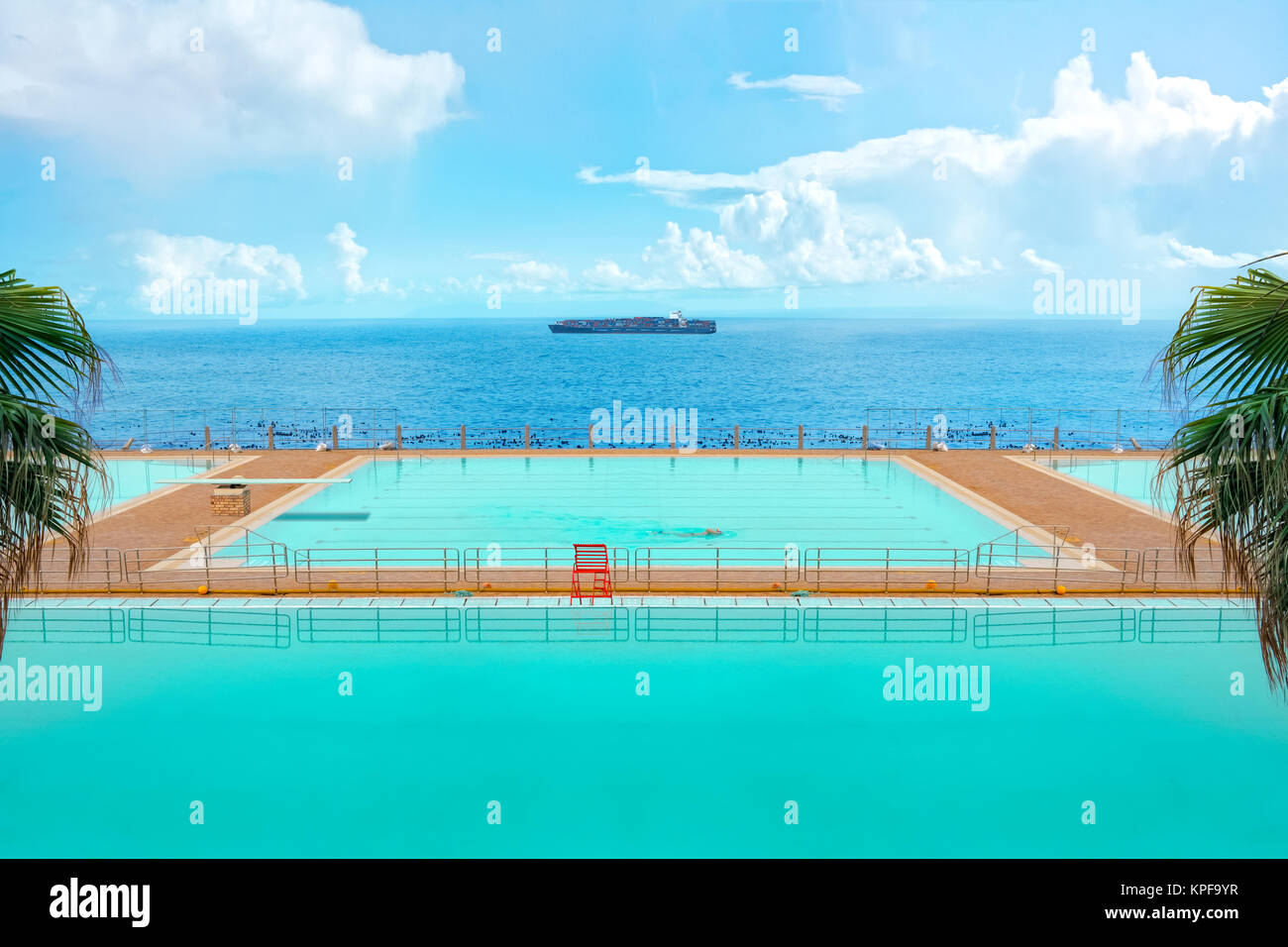 Outdoor swimming pool with turquoise water, surrounded of palms and an ...