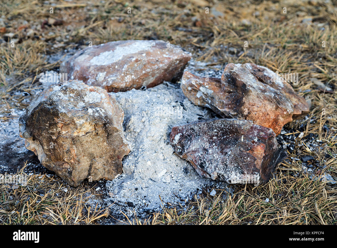 Used fire pit with surrounding stones and cinders Stock Photo - Alamy
