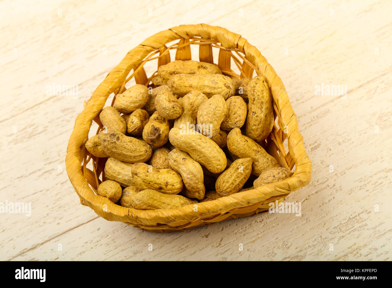 Unpeeled peanuts heap in the basket over wooden baclground Stock Photo ...