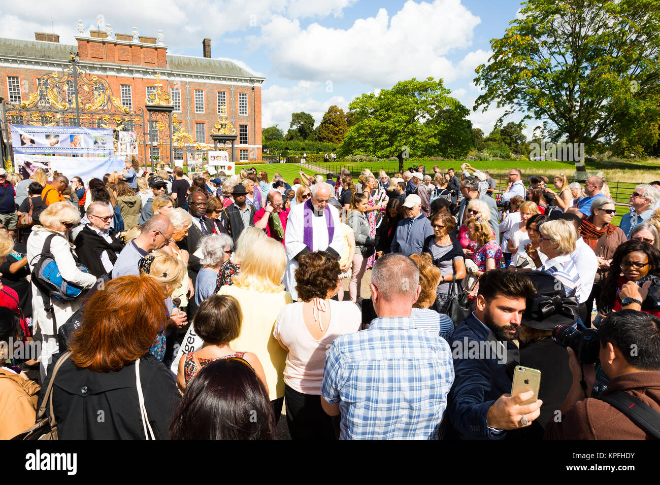 London, UK. A crowd gathers around retired pastor Father Frank Gelli as ...