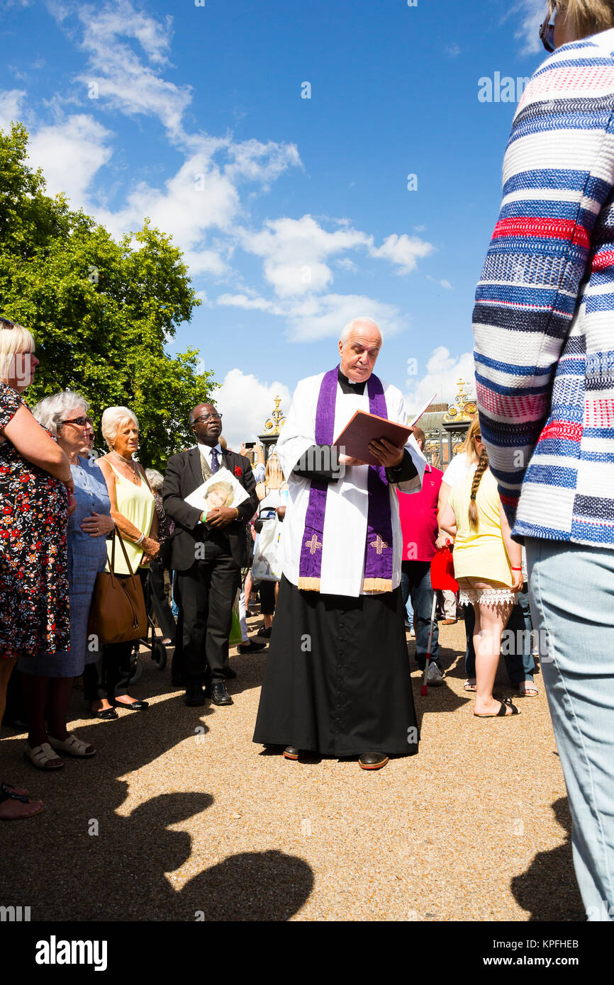 London, UK. A crowd gathers around retired pastor Father Frank Gelli as ...