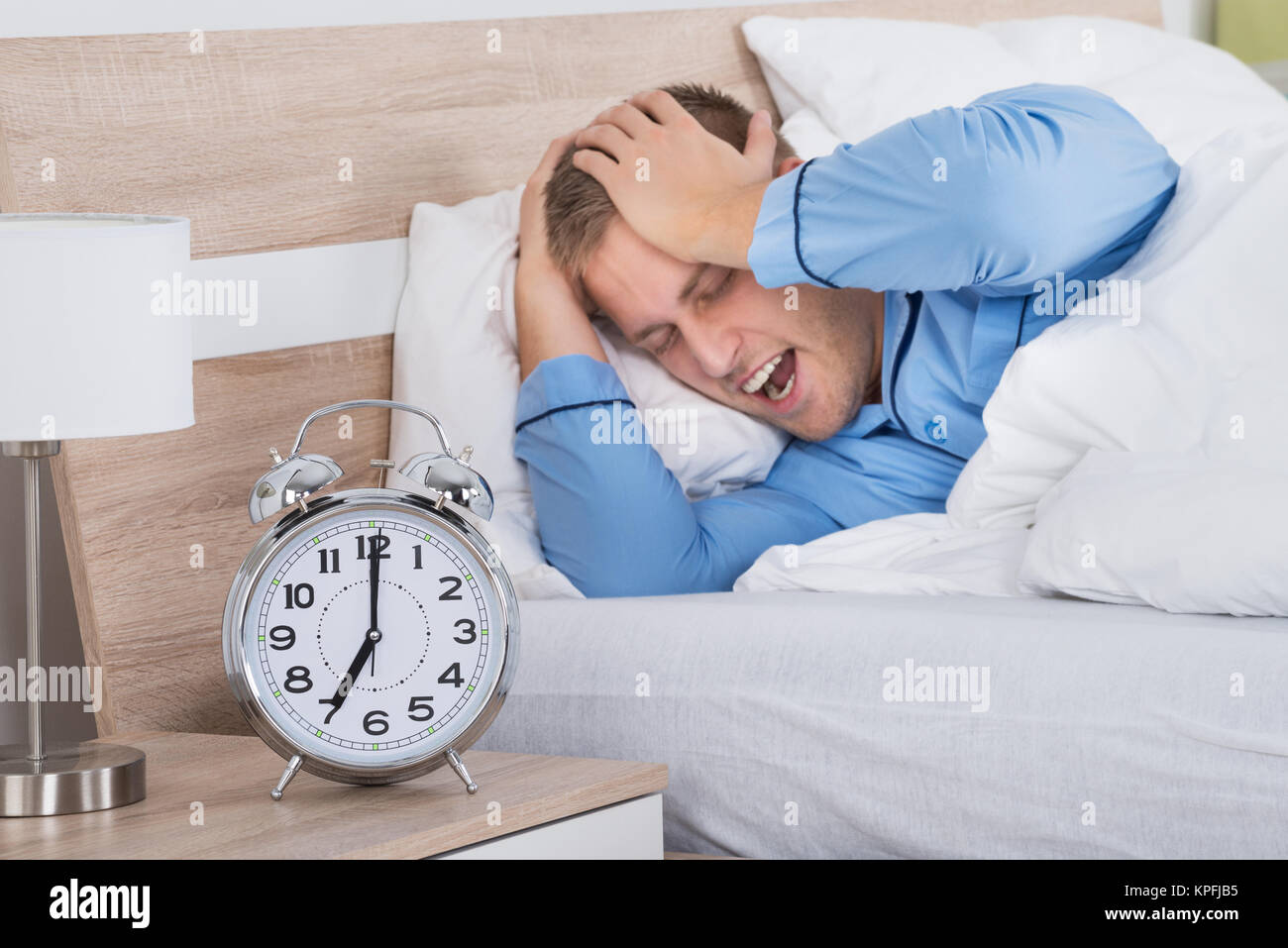 Sleeping Man Disturbed By Ringing Alarm Clock Stock Photo - Alamy