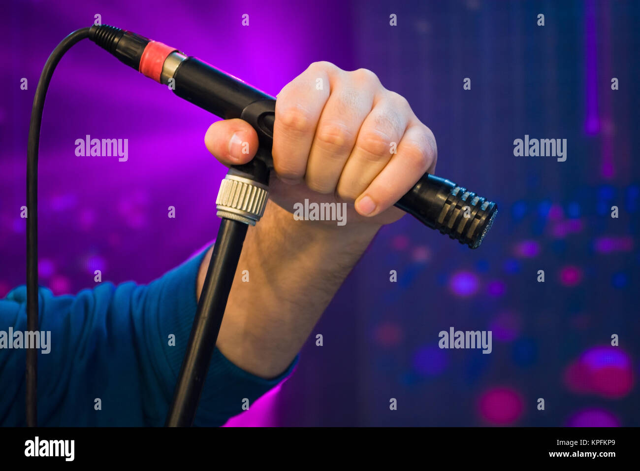 man holding microphone in hand on stage background Stock Photo - Alamy