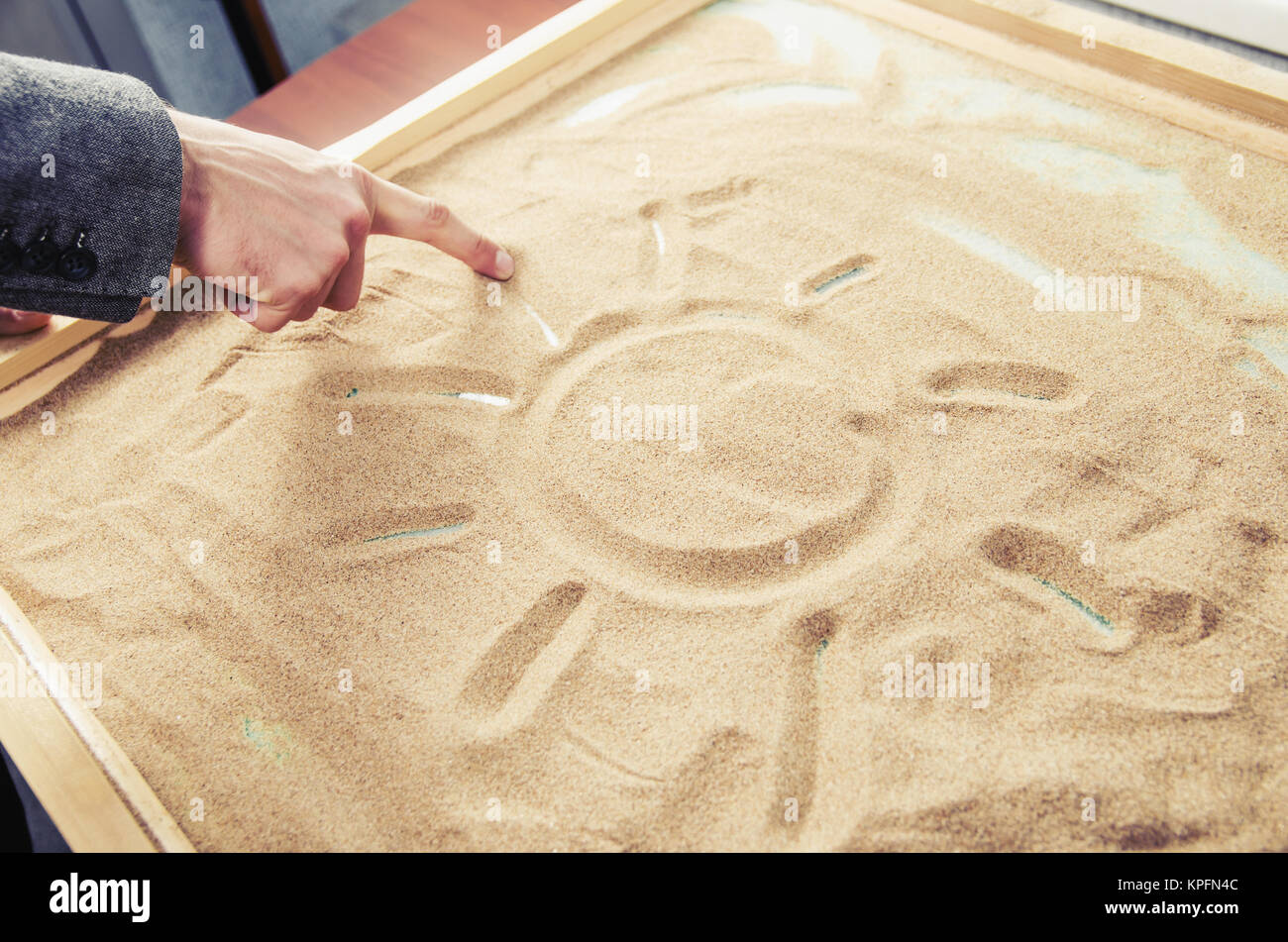 a man draws by his finger on the sand symbol of the sun. toned Stock ...