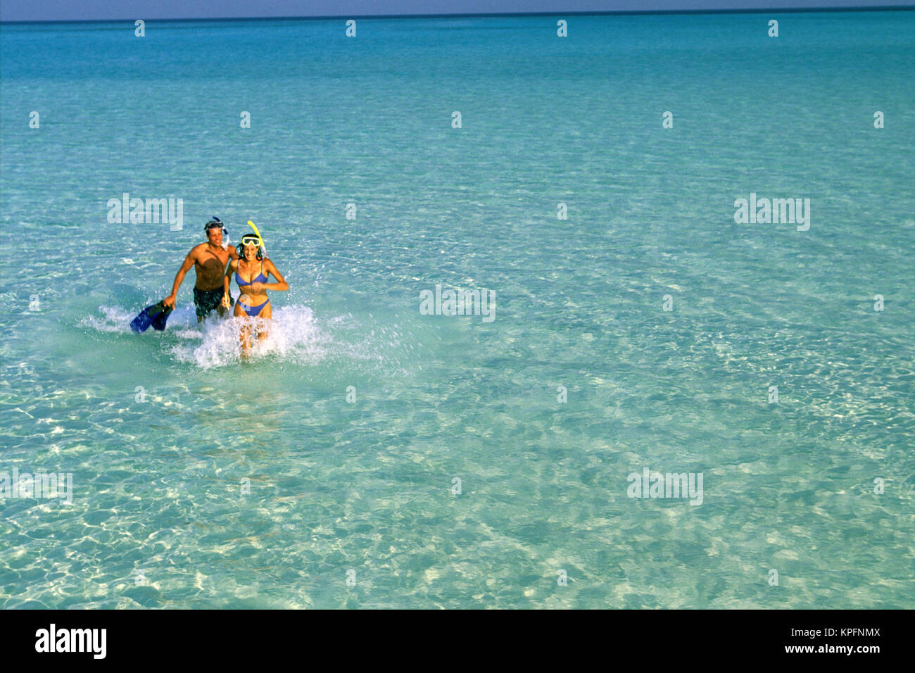 Asia, Maldives. Couple running through waves with diving gear (MR Stock ...