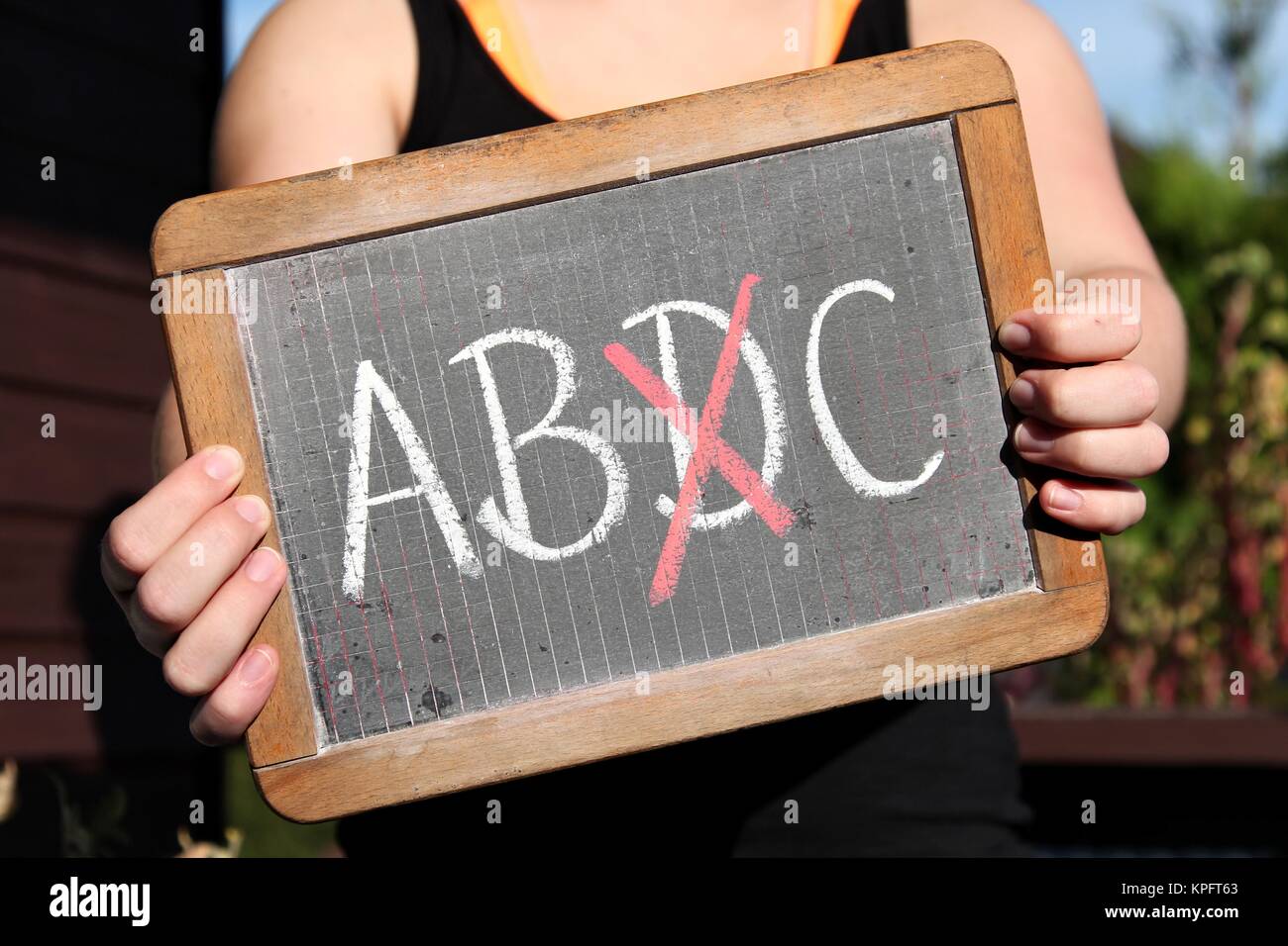 ABC with mistake written with chalk on slate shown by young female ...