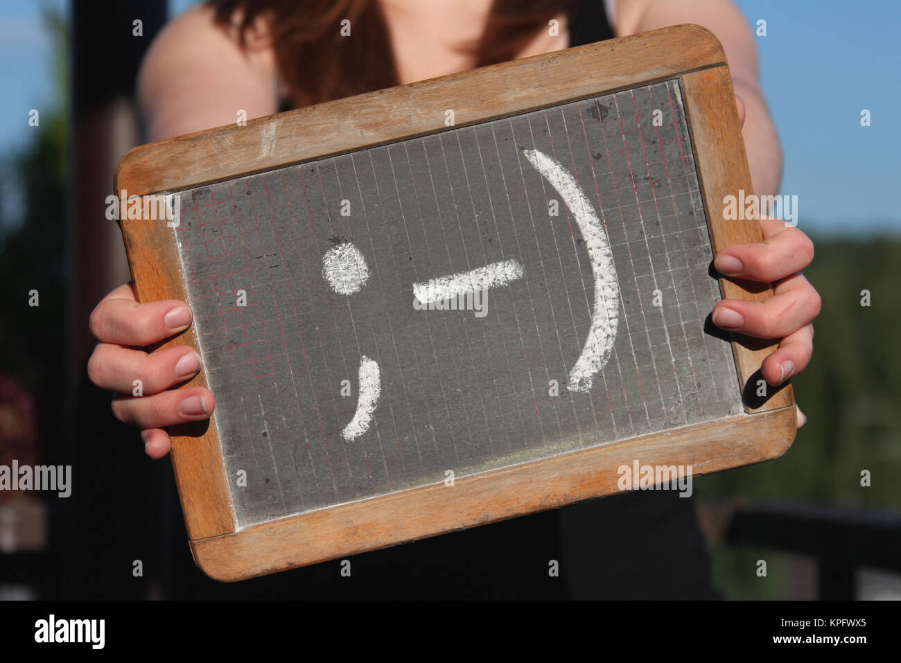 emoticon sketched with chalk on slate shown by young female Stock Photo ...