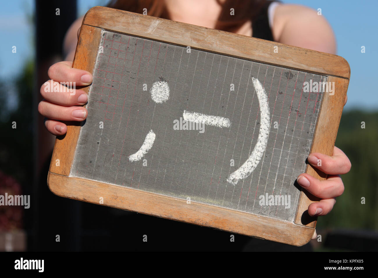 emoticon sketched with chalk on slate shown by young female Stock Photo ...