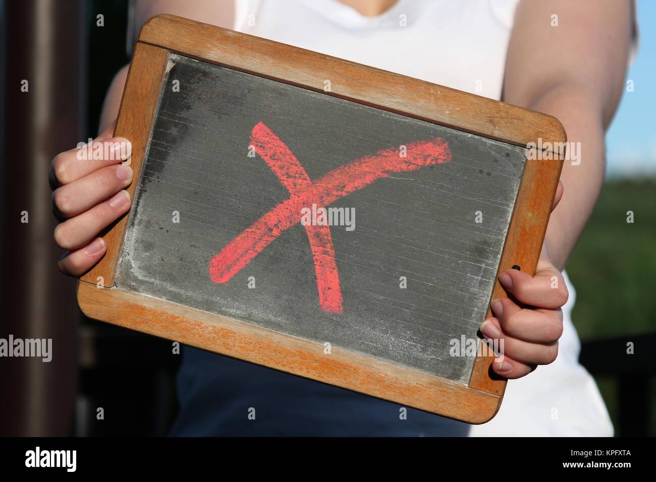 red mistake sign sketched with chalk on slate shown by young female ...