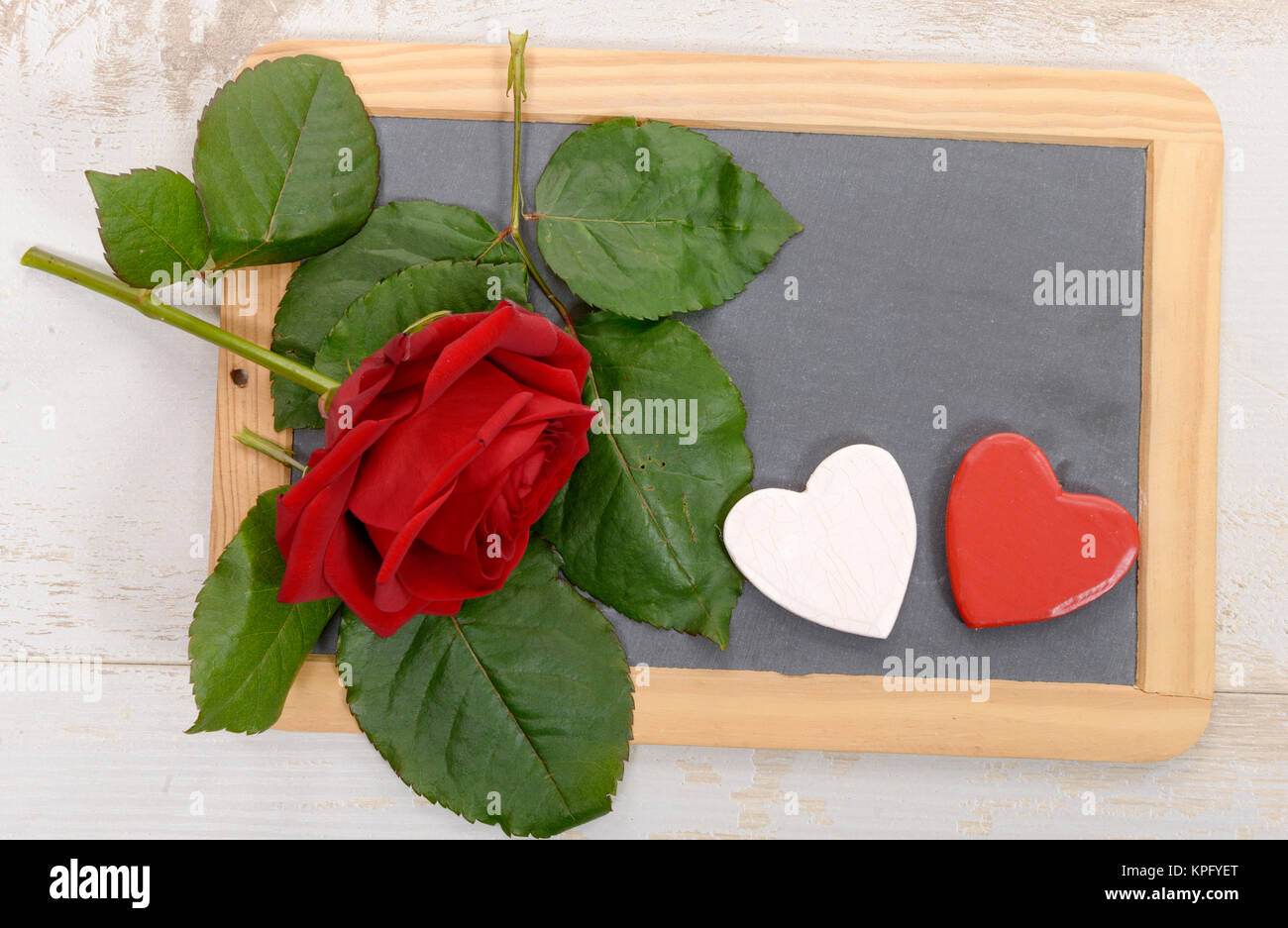 red rose and black slate on a wood background Stock Photo - Alamy