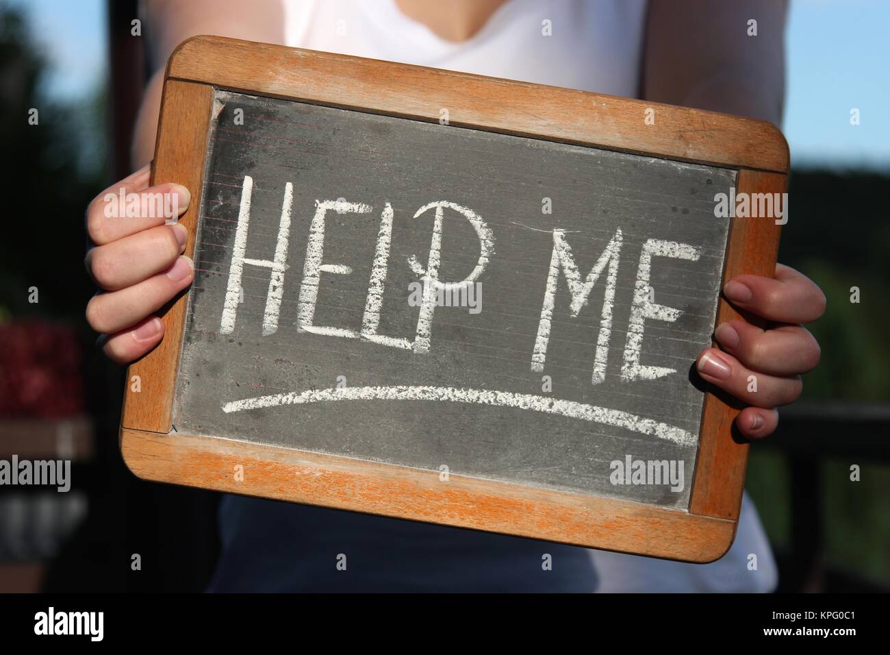 HELP ME written with chalk on slate shown by young female Stock Photo ...