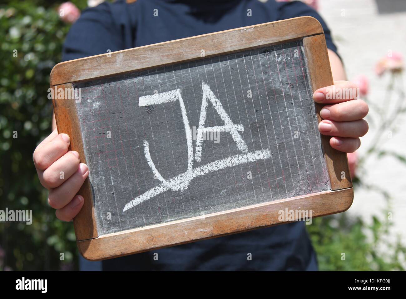 JA (yes in German) written with chalk on slate shown by young female ...
