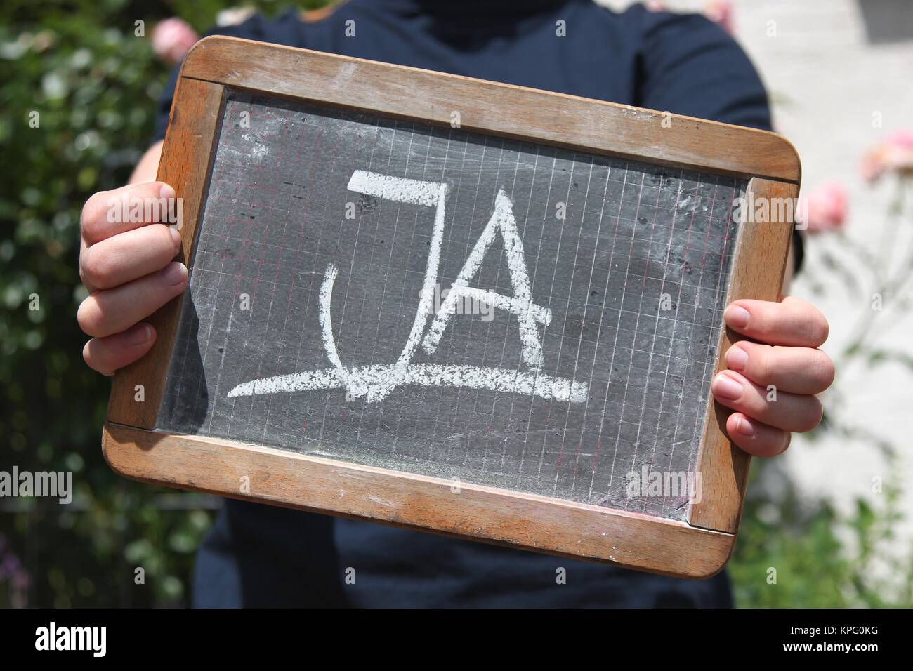 JA (yes in German) written with chalk on slate shown by young female ...
