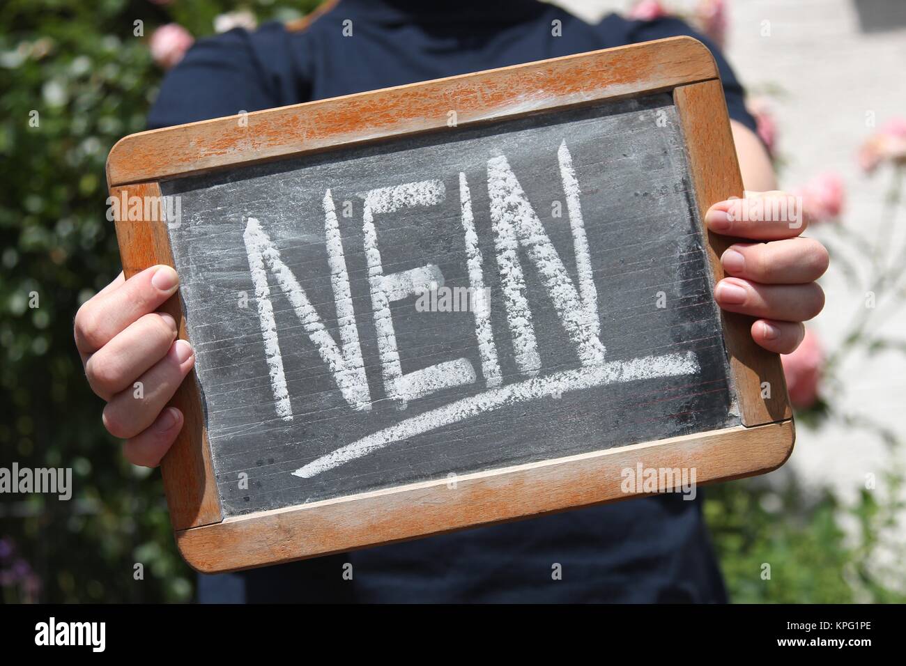 NEIN (no in German) written with chalk on slate shown by young female ...