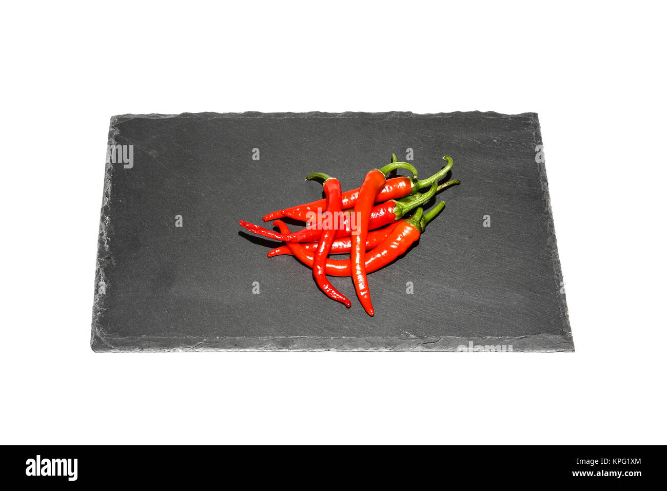Red chilli peppers laid on a slate platter isolated on a white ...