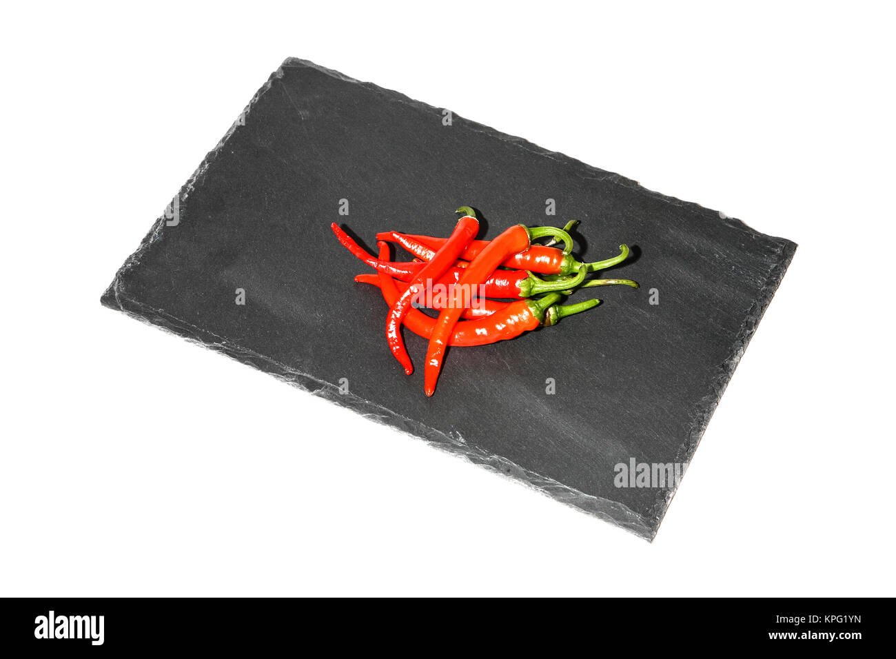 Red chilli peppers laid on a slate platter isolated on a white ...