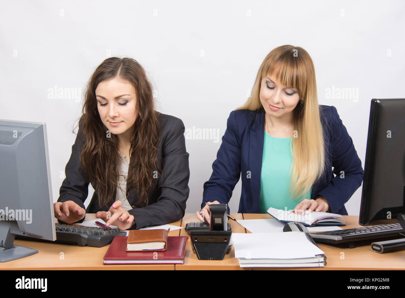 Two young business women working in the office at the workplace at the ...