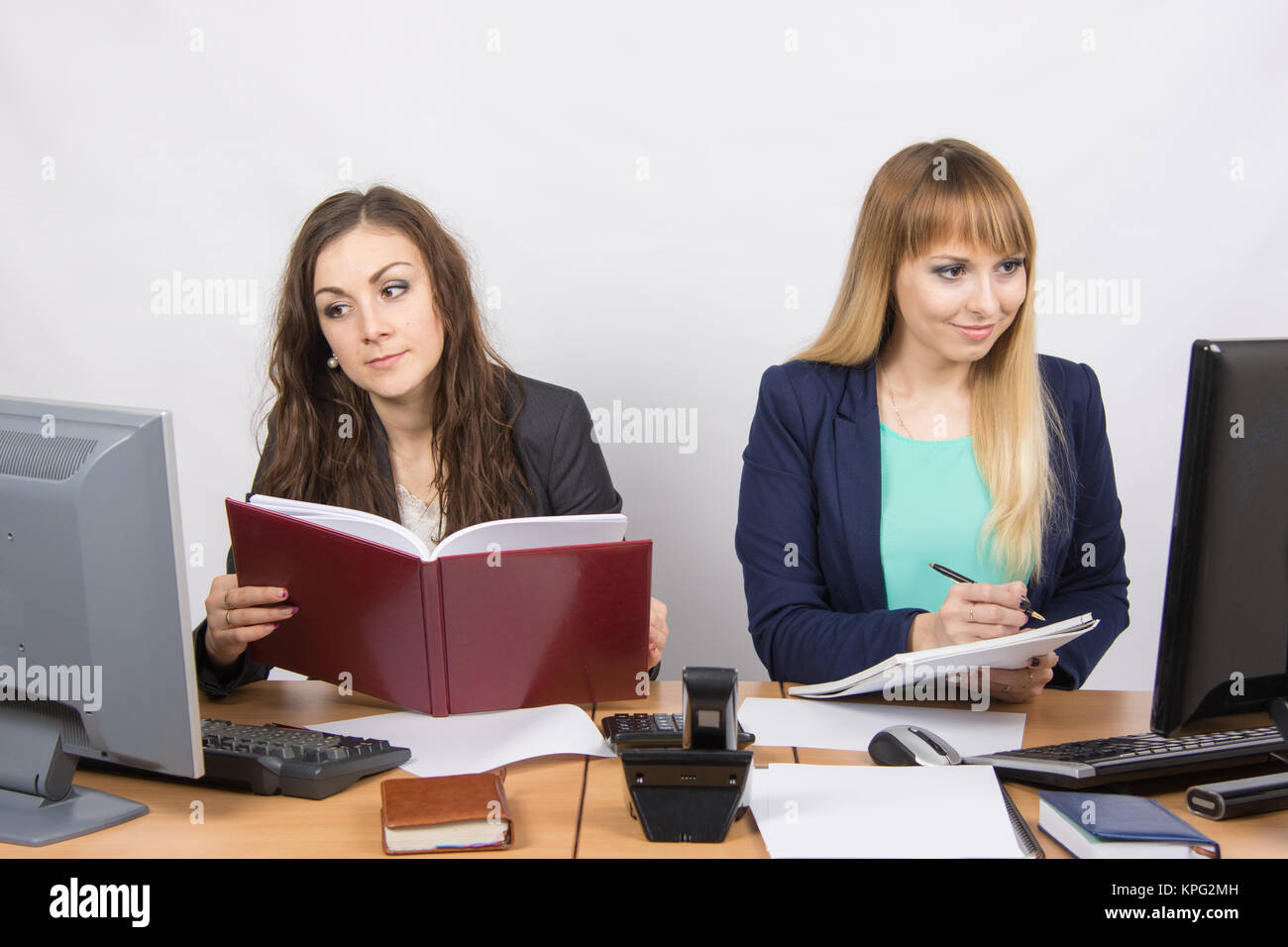 Two business women working with one rival desktop Stock Photo - Alamy