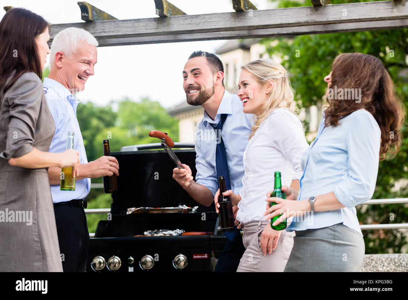 team of colleagues during grilling after evening Stock Photo - Alamy