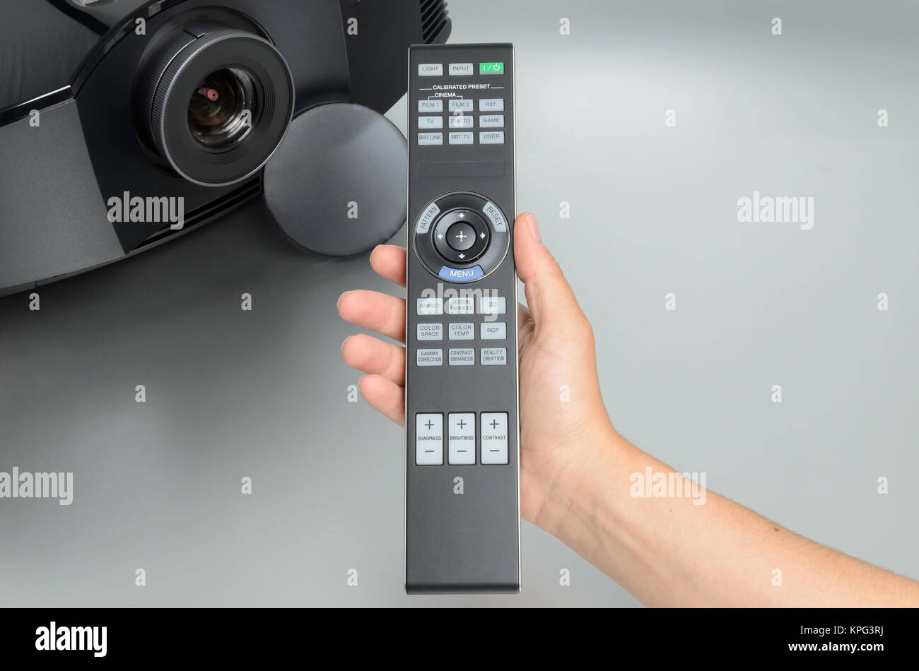 Huge black home cinema projector, hand presenting the remote Stock ...