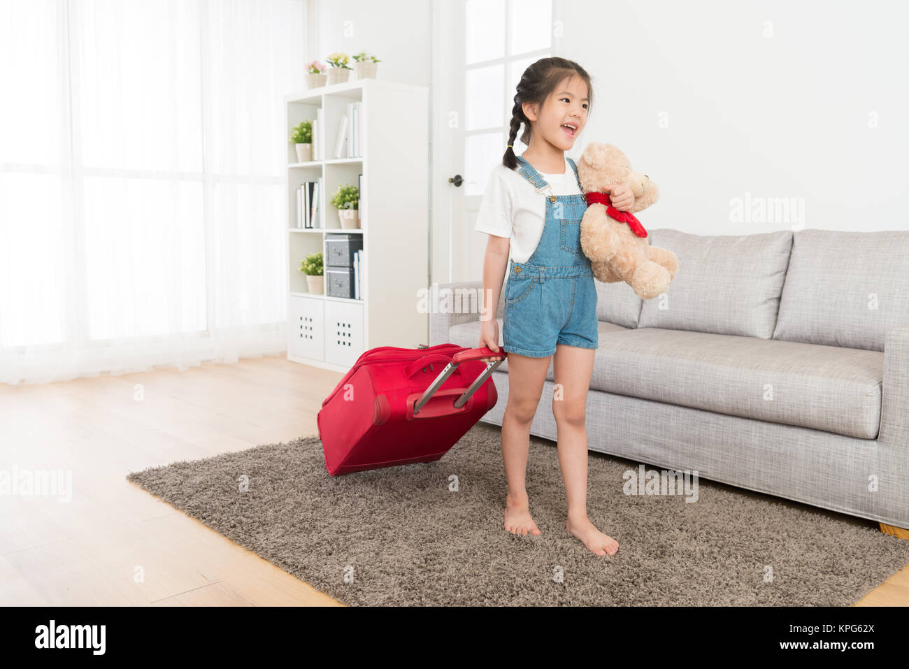 happy beautiful kid girl pulling personal luggage suitcase ready to ...