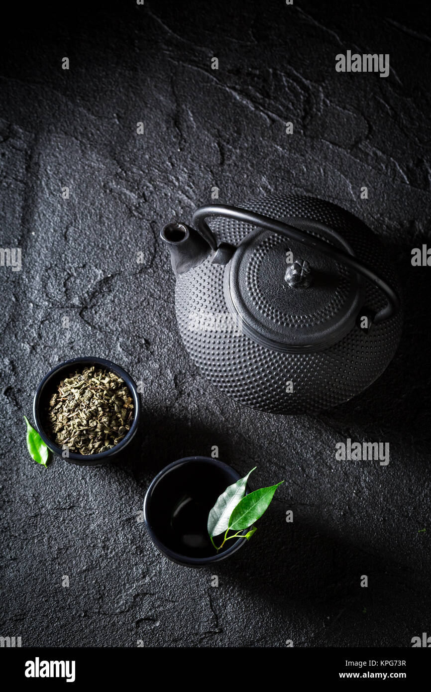 Grains of green tea in teacup on black rock Stock Photo - Alamy