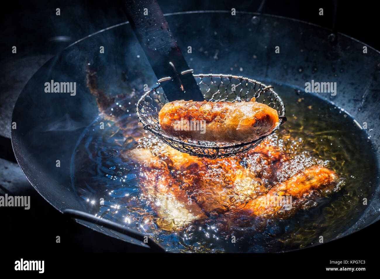 Homemade spring rolls frying in hot oil in black pan Stock Photo - Alamy