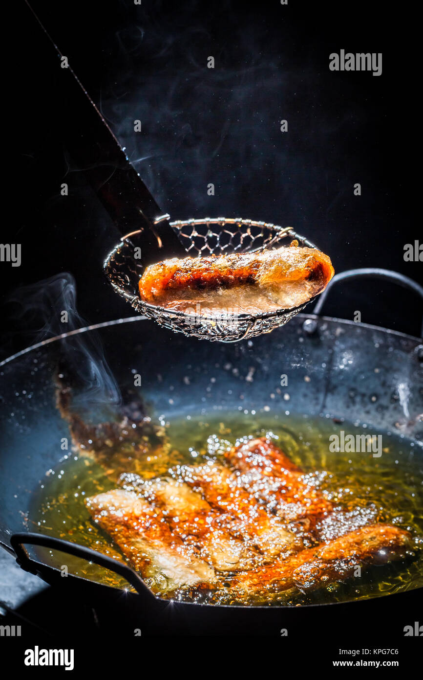 Fresh spring rolls frying in black pan Stock Photo - Alamy